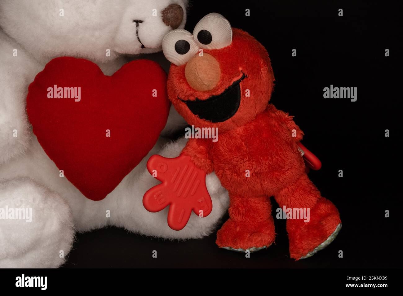 White stuffed teddy bear with red plush heart and happy Elmo muppet ...