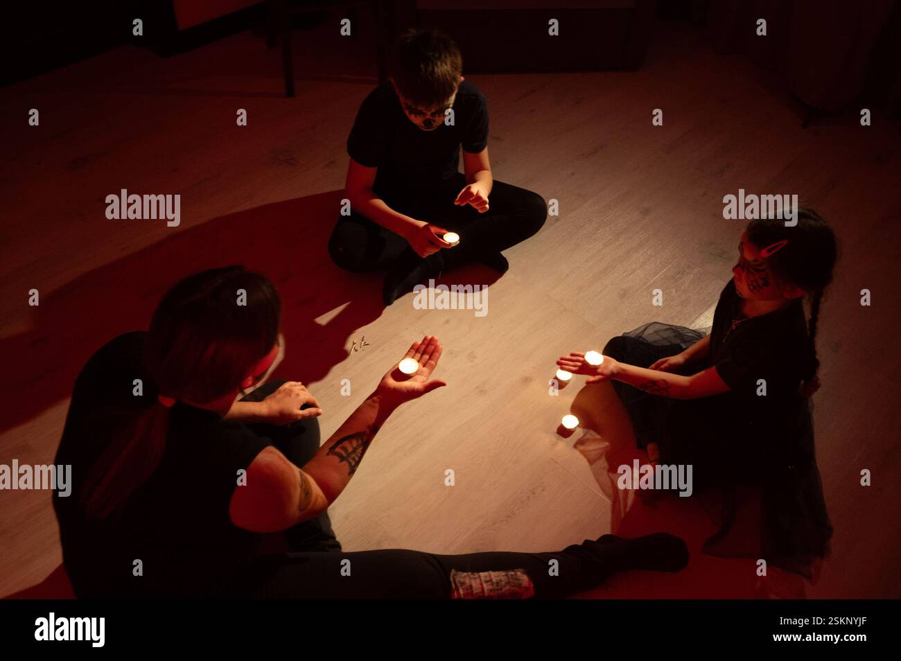 Three children and an adult gather in a circle, each holding a small ...