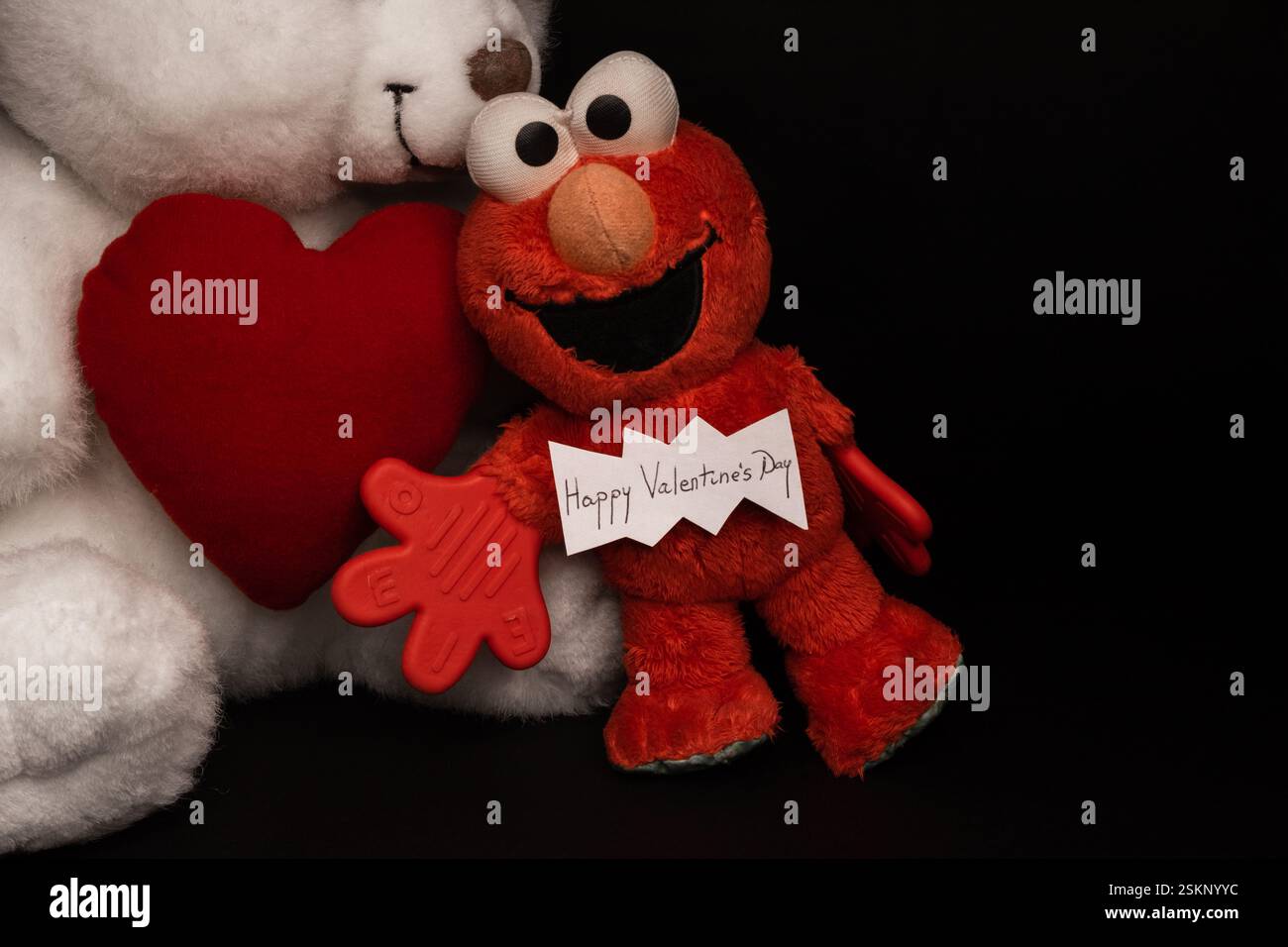 White stuffed teddy bear with red plush heart, happy Elmo muppet with ...