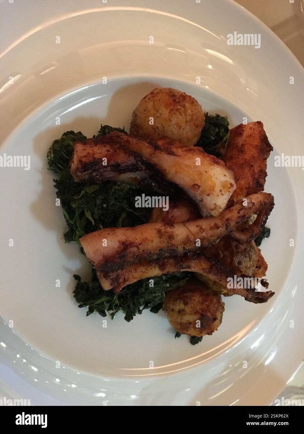 Grilled octopus with crispy potatoes and sauteed greens. Savory seafood ...