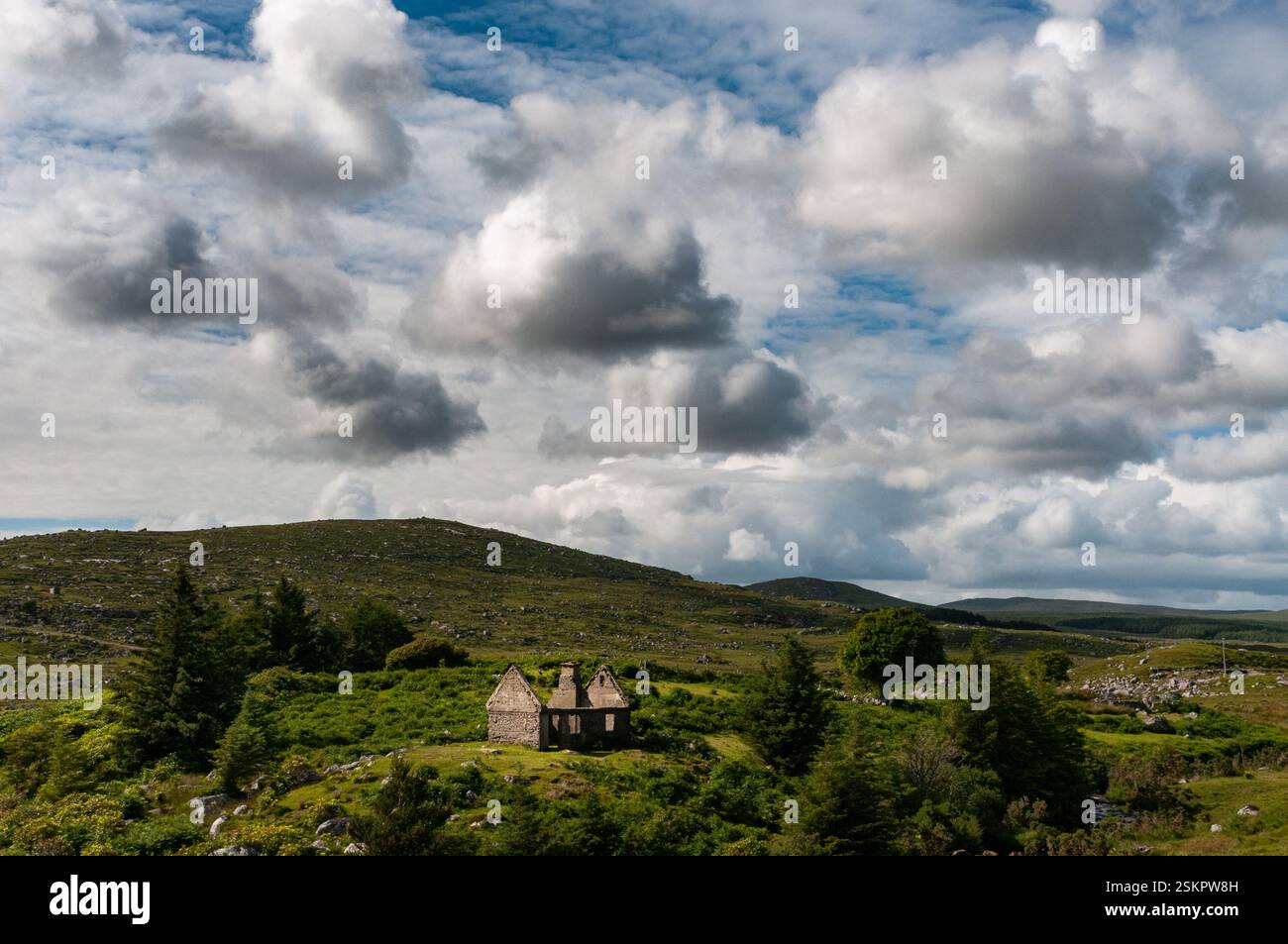 The remains of an ancient stone house sits among trees and green ...