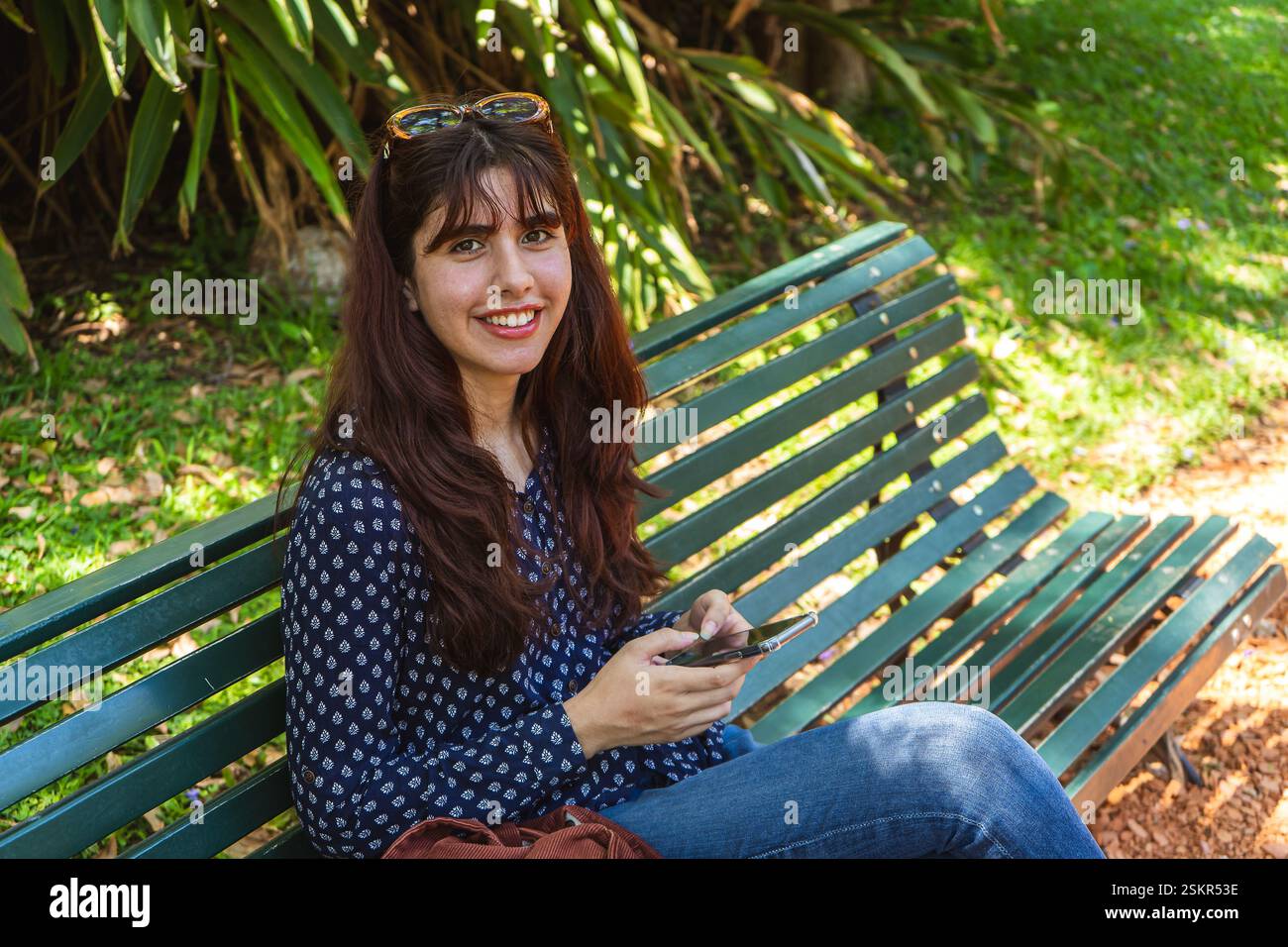 University student using mobile phone app while sitting on bench in a ...