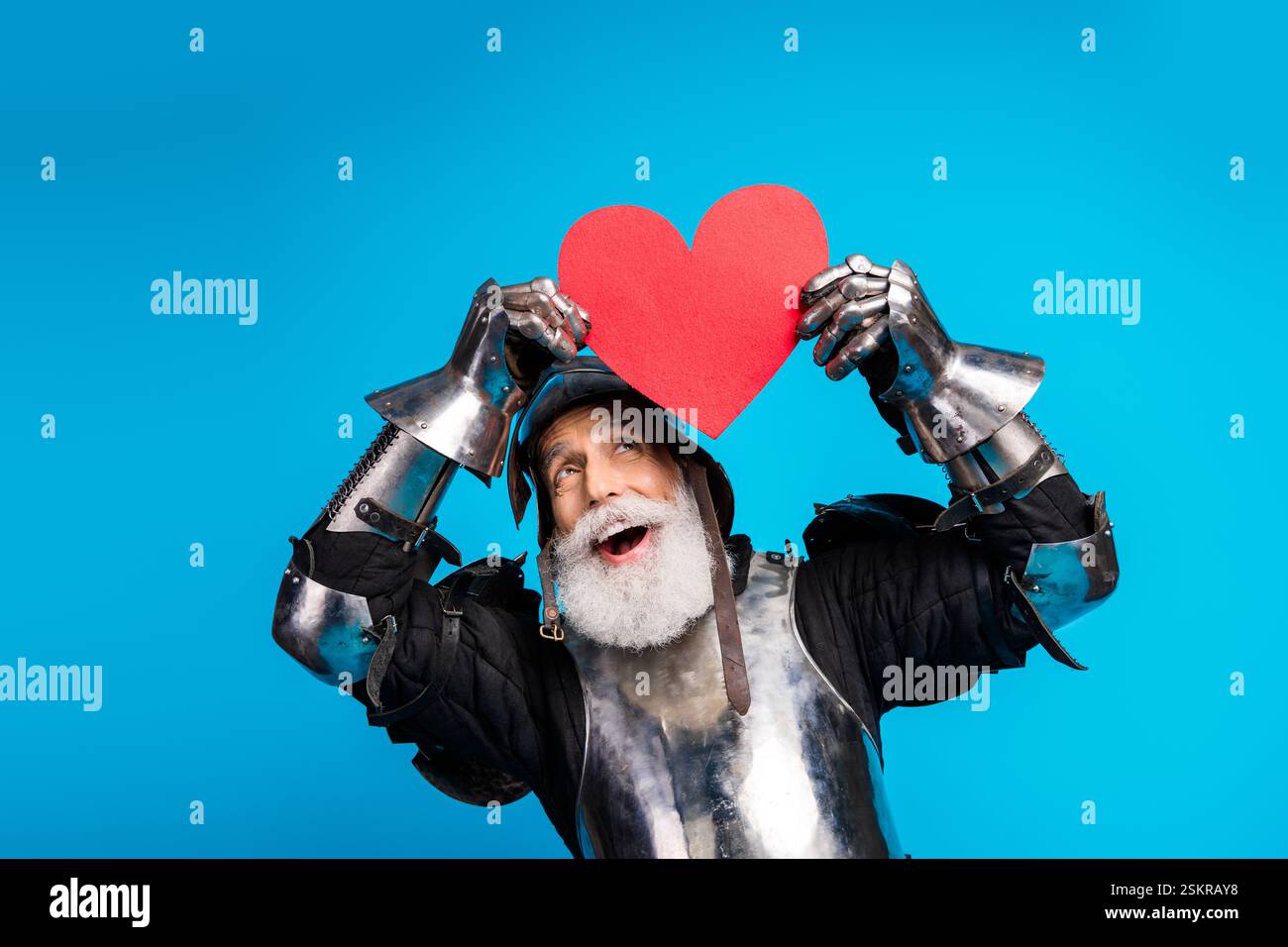 Knight wearing metal armor holding red heart shape on blue background ...