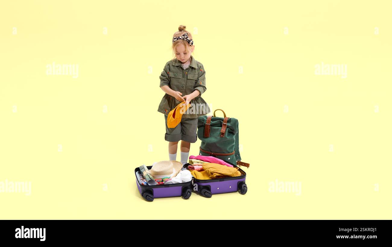 Pretty girl, child in casual clothes standing next to open suitcase ...