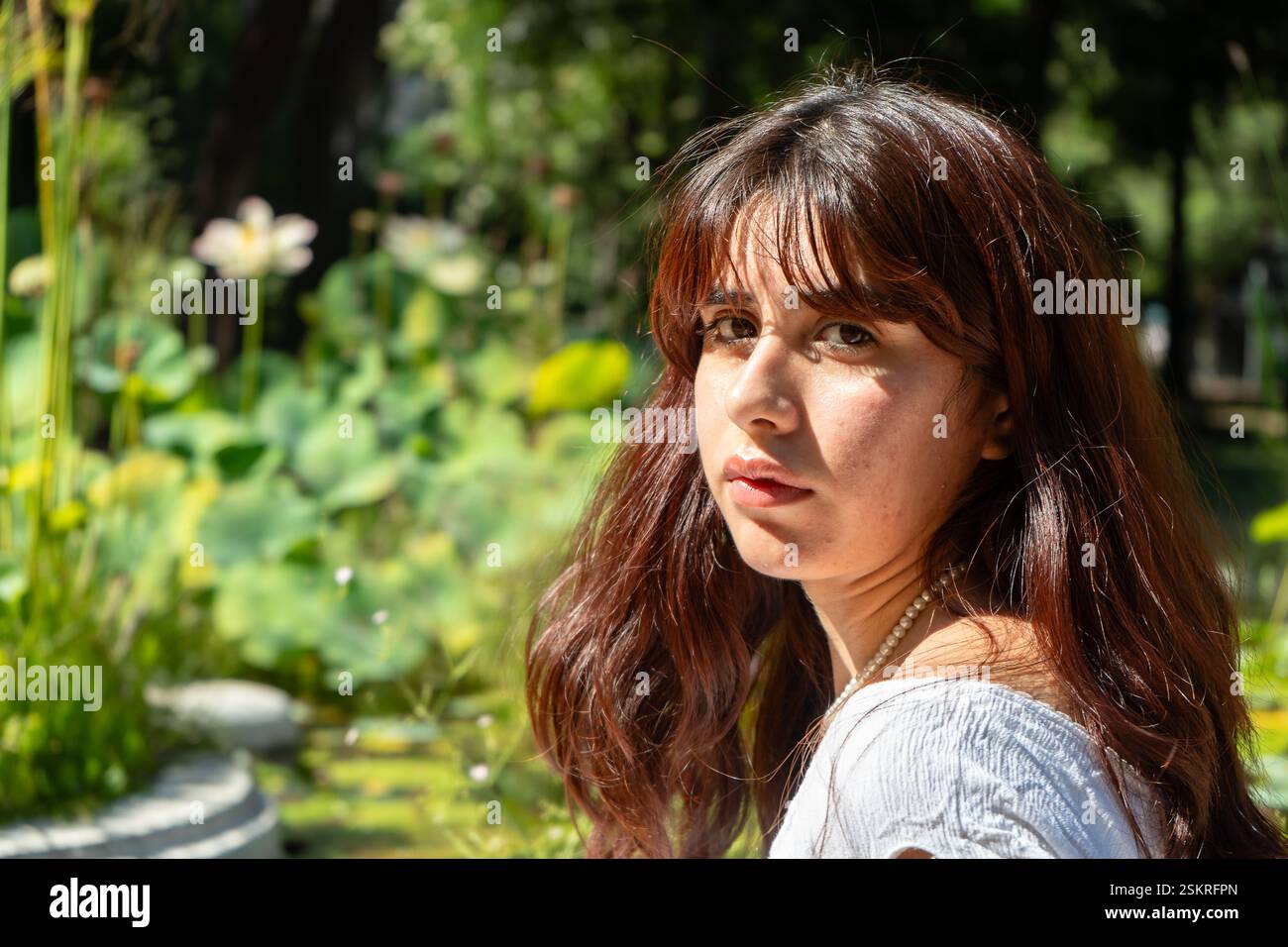 Beautiful young woman with long brown hair is posing in a botanical ...