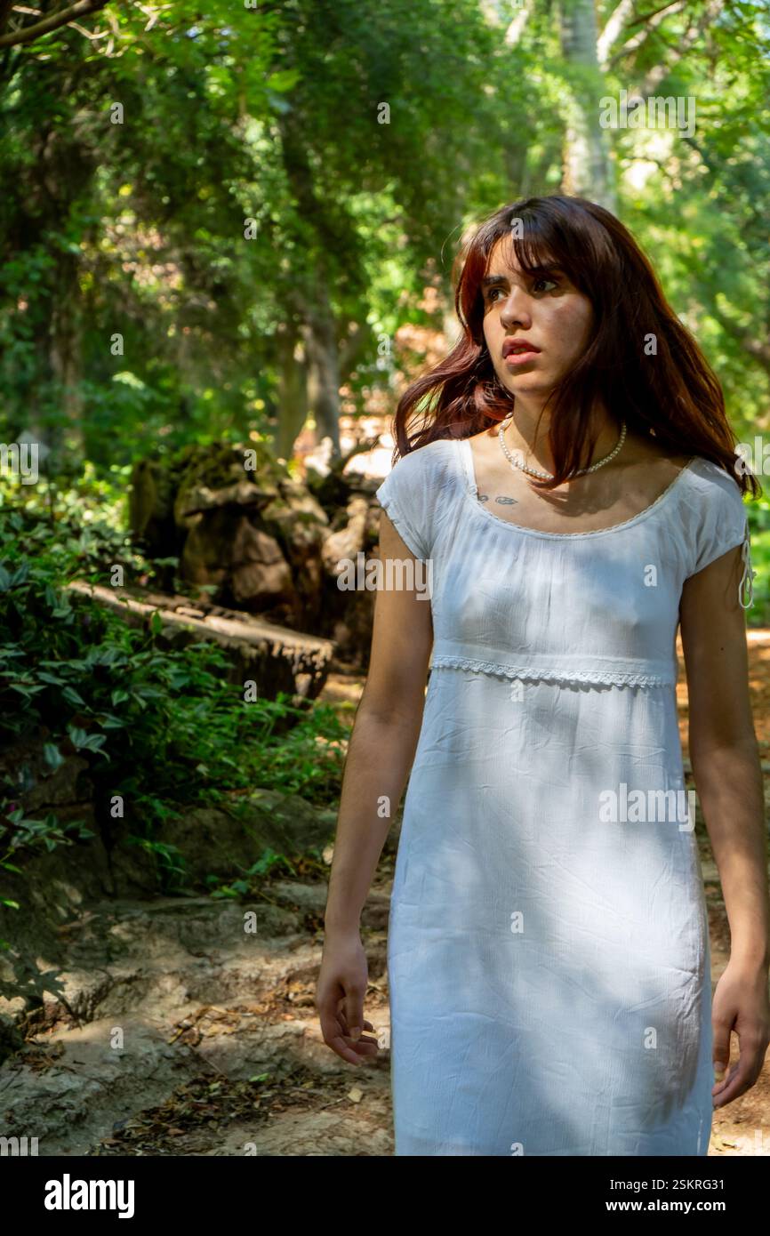 Model walking in a forest wearing a white dress, enjoying nature and ...