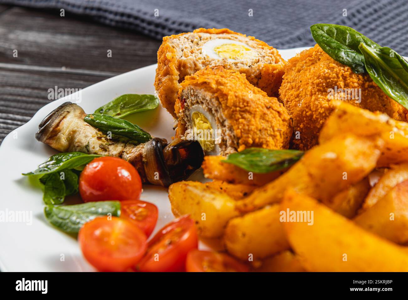 A plate showcases golden-breaded meat rolls filled with egg ...