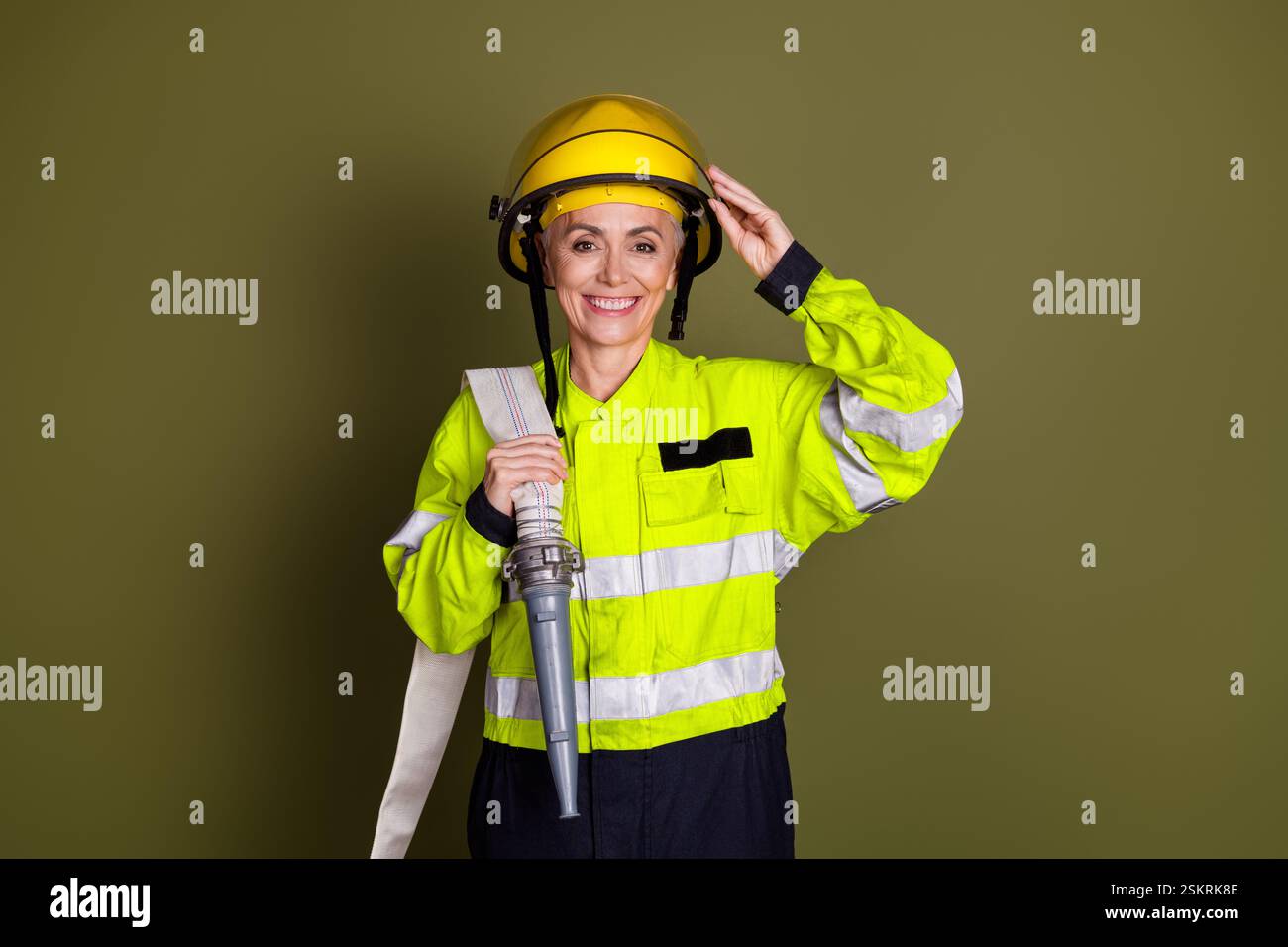 Confident female firefighter wearing yellow hardhat and high-visibility ...