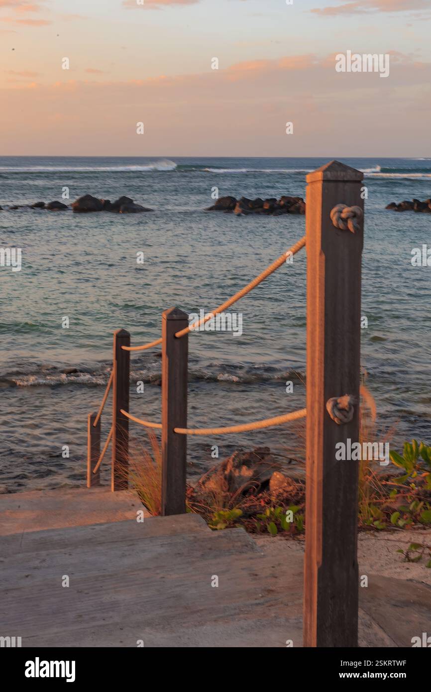 A wooden staircase with rope railing leading down to the ocean at ...