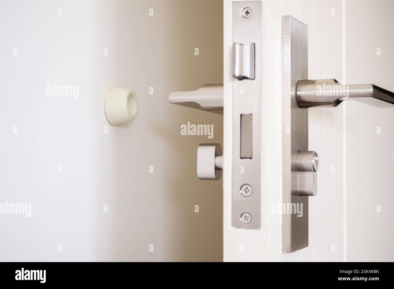 Wall mounted door stopper with modern door handle Stock Photo - Alamy