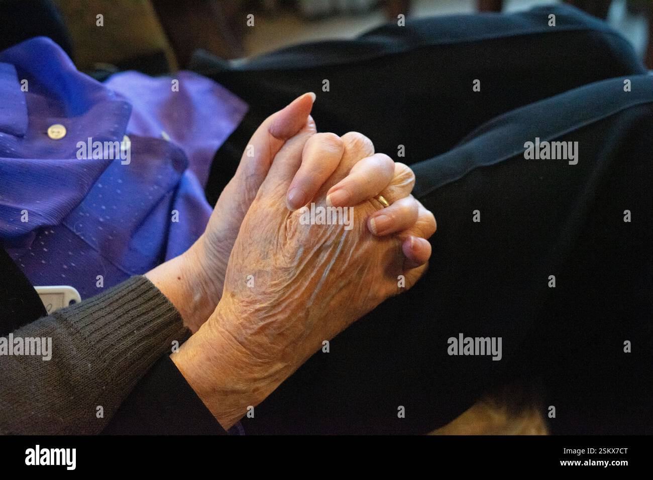 Elderly women's hands clasped together, revealing wrinkles and a ...