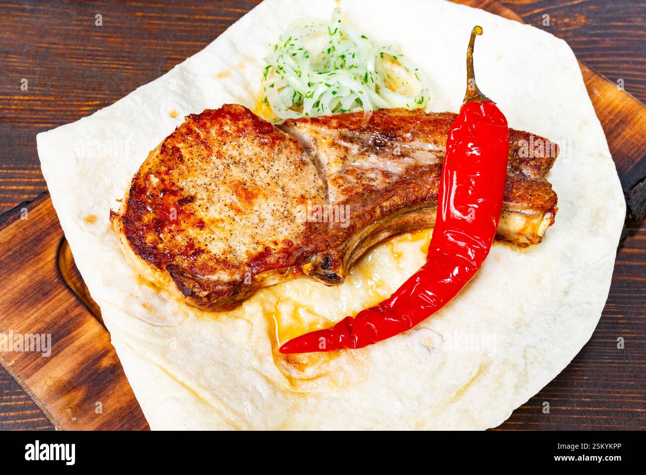 Juicy grilled pork is presented on flatbread with a side of finely ...