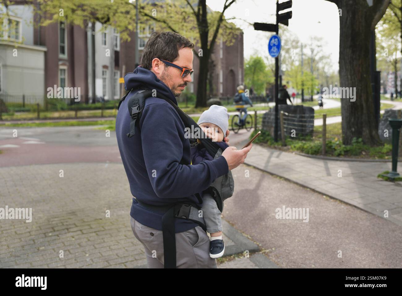 A father carrying his child in a baby sling kangaroo Stock Photo - Alamy
