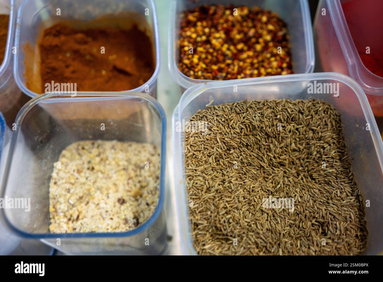 Different colorful indian spices filling transparent plastic containers ...