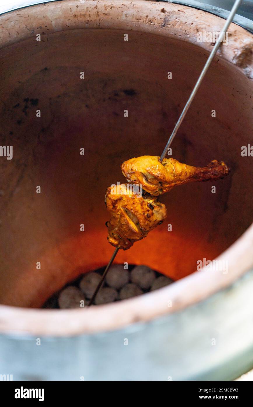 Delicious tandoori chicken cooking in a traditional clay oven ...