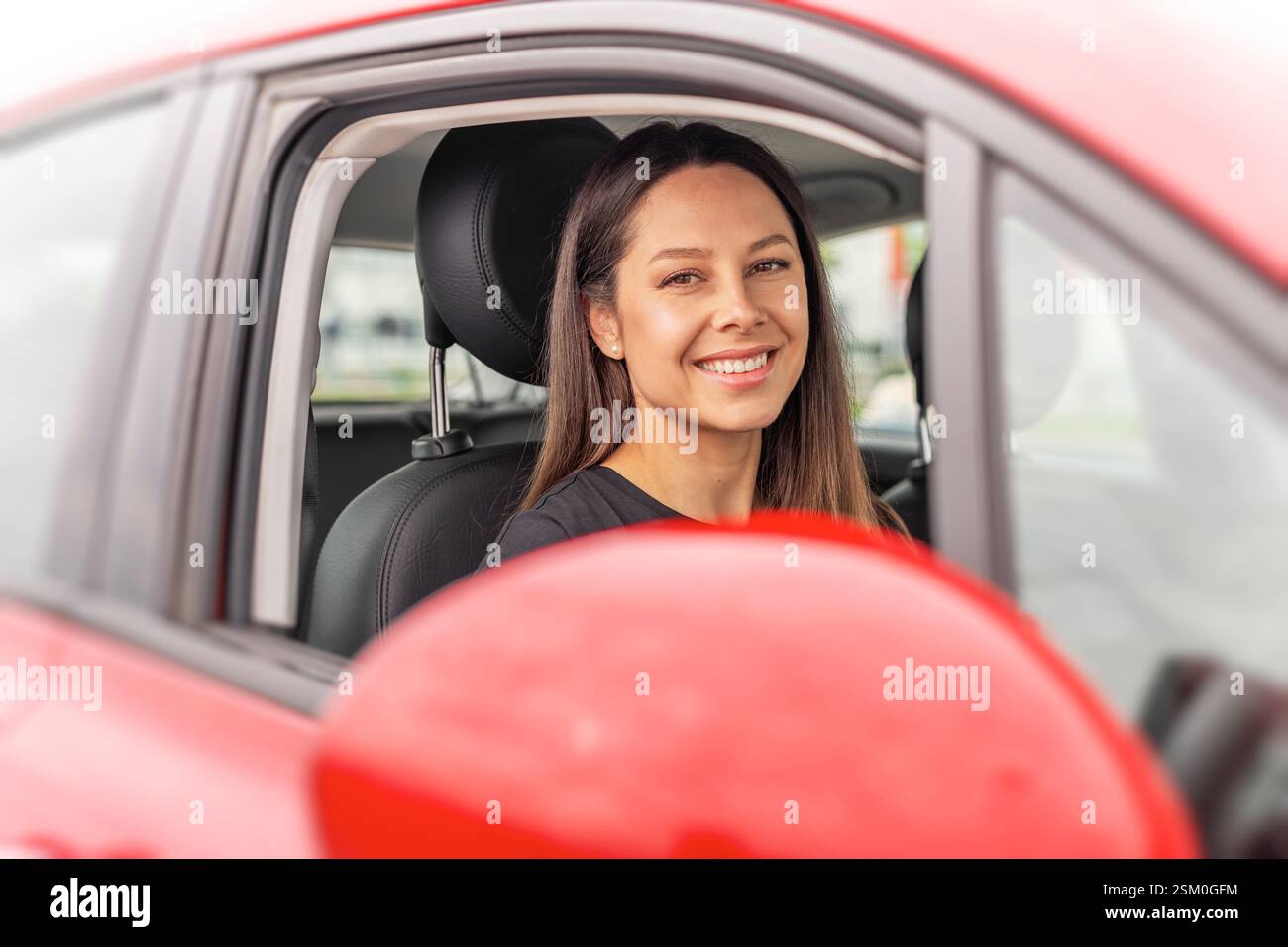 A young woman with long brown hair and a bright smile sits in the ...