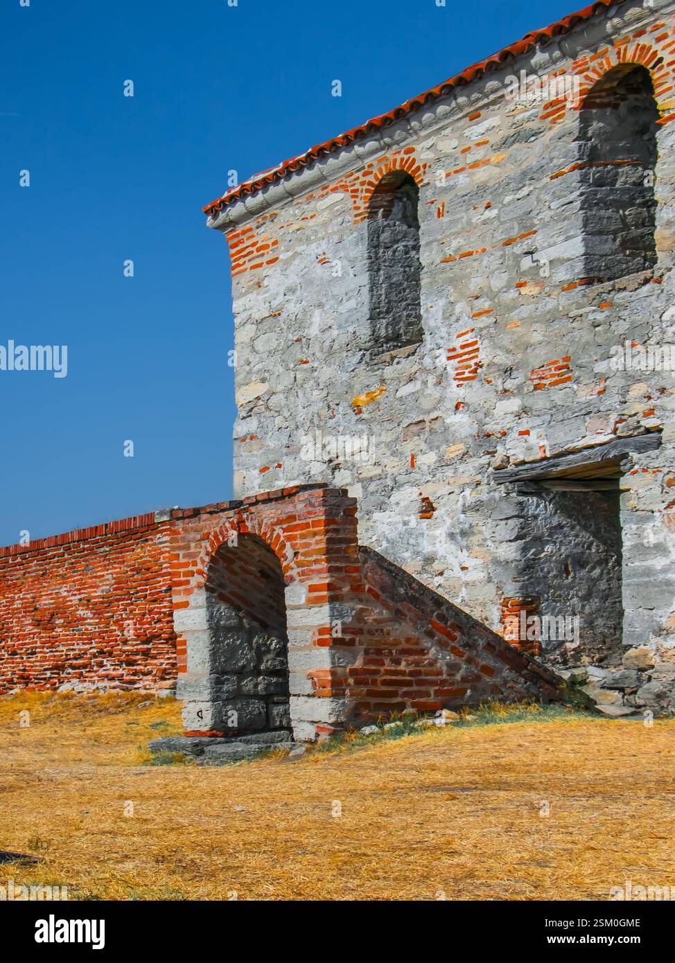 A weathered stone building features exposed brick elements, with a ...