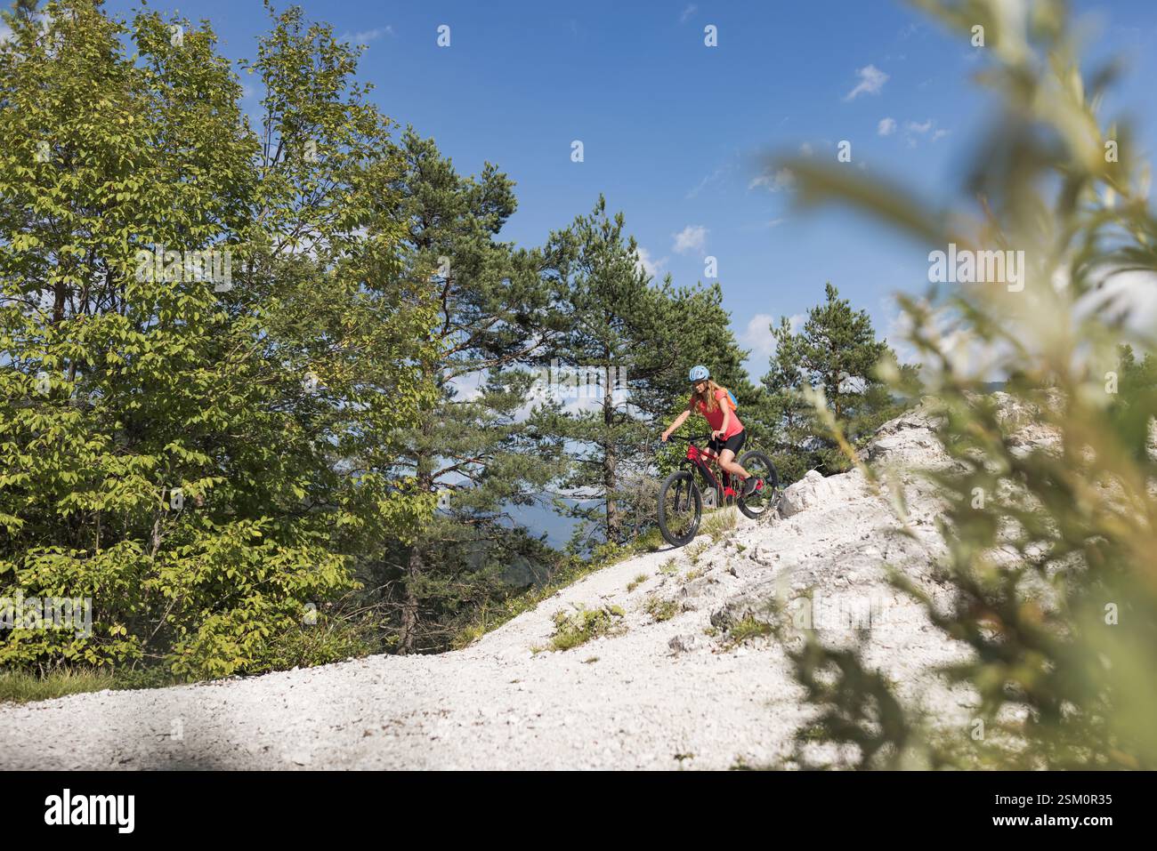 Female biker riding an electric mountain bike on a fine white stone ...