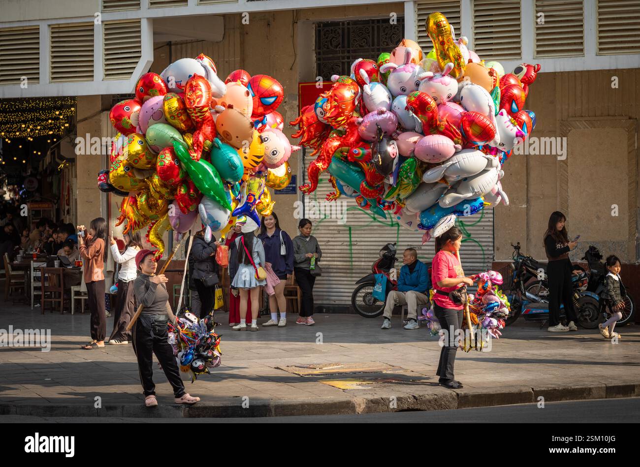 Two Vietnamese women sell colourful balloons in the shapes of animals ...