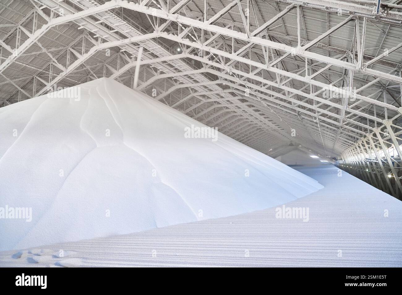 Large white salt pile stored in a chemical plant warehouse with ...