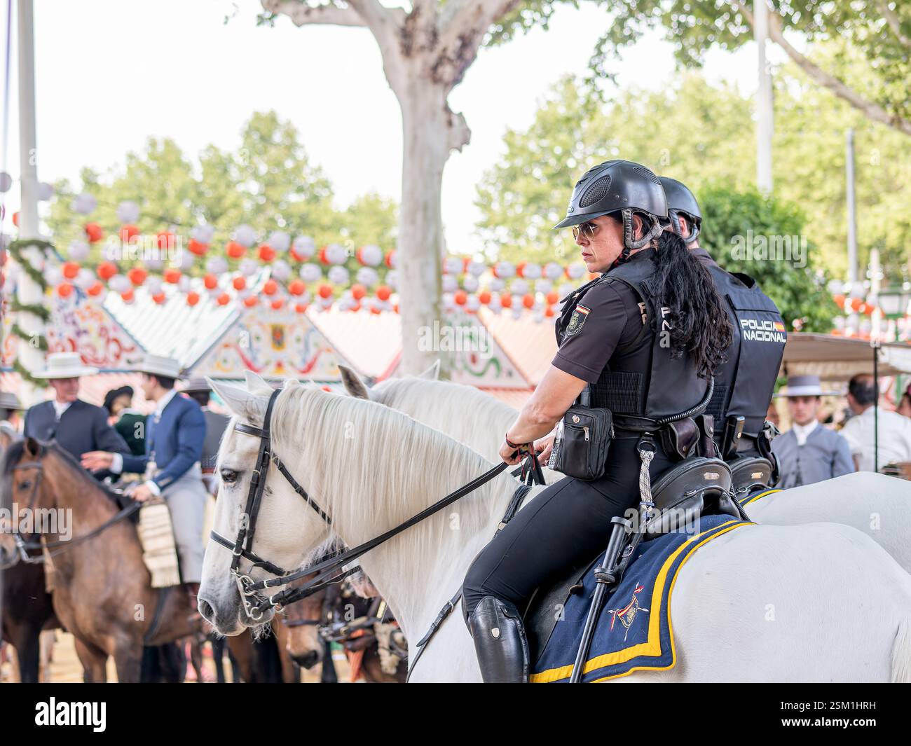 A female police officer in uniform, riding horses at Seville Fair Stock ...
