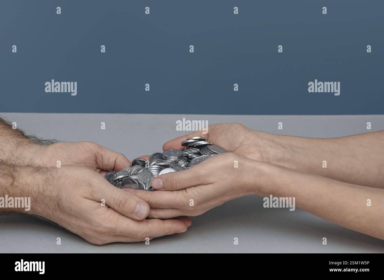 Male hands embrace female hands with pile of coins. Gray background ...