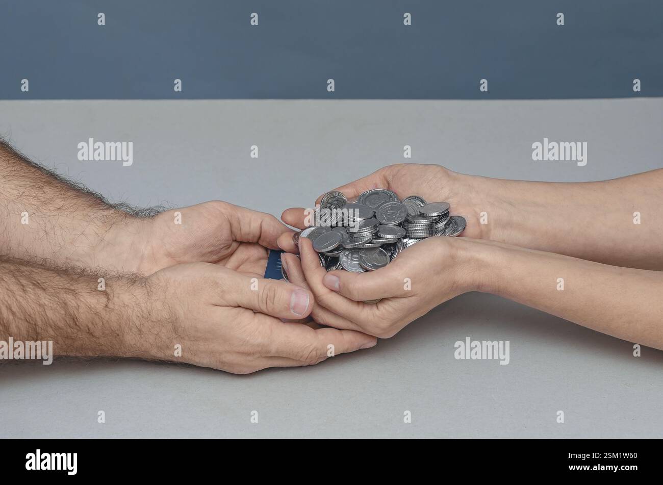Male hands embrace female hands with pile of coins. Gray background ...