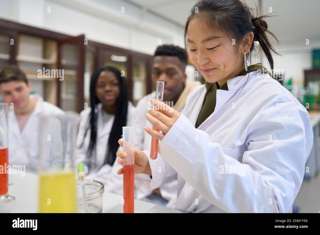 Young scientist pouring chemical liquid in laboratory glassware during ...