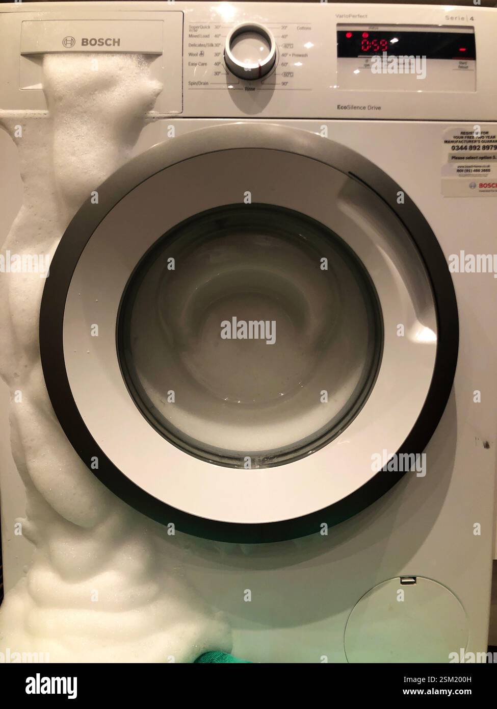 A broken washing machine overflowing with bubbles Stock Photo - Alamy