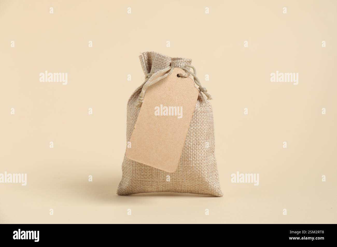 One burlap bag with tag on beige background Stock Photo - Alamy