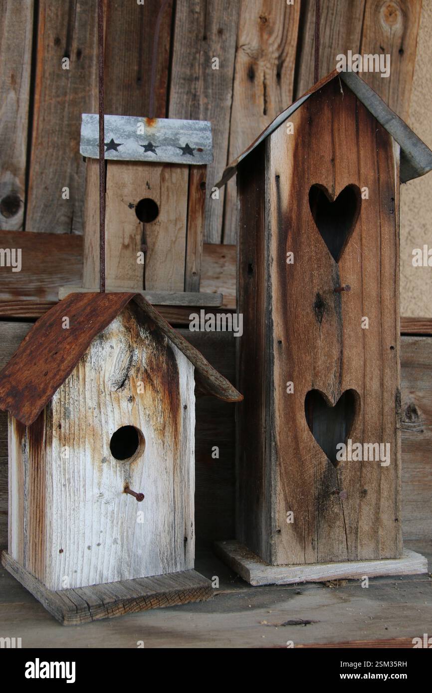 Three different sized wooden birdhouses on a wood bench. On two story ...