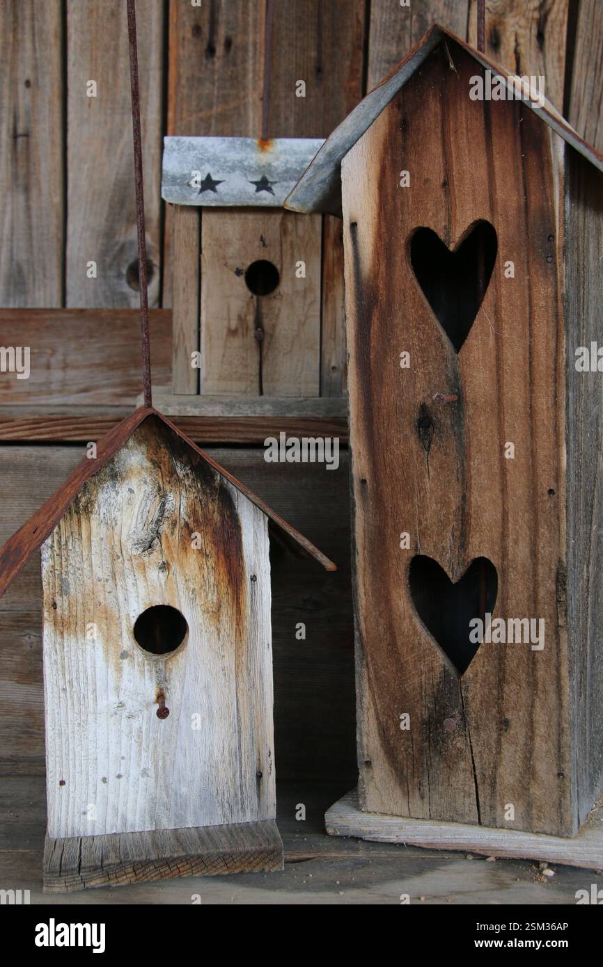 Three different sized wooden birdhouses on a wood bench. On two story ...