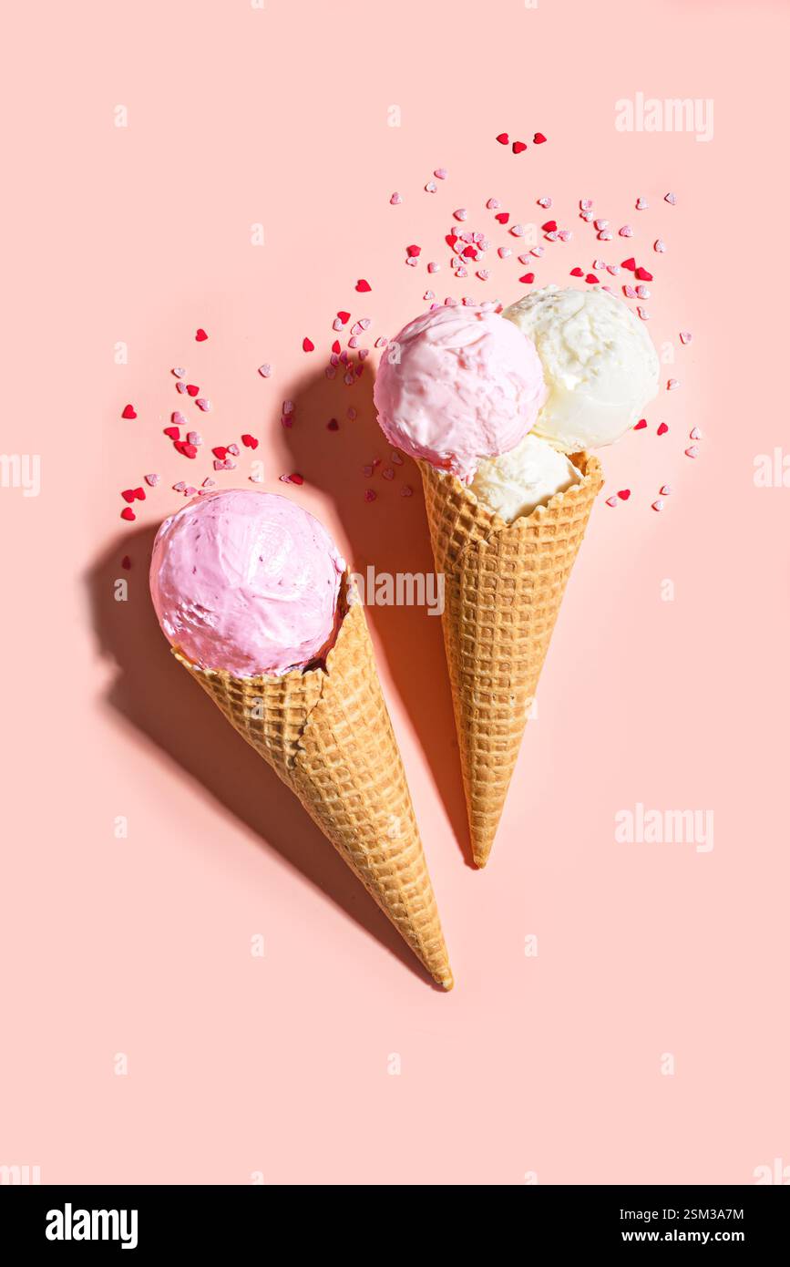 Two ice cream cones with heart shaped sugar sprinkles on pink pastel ...