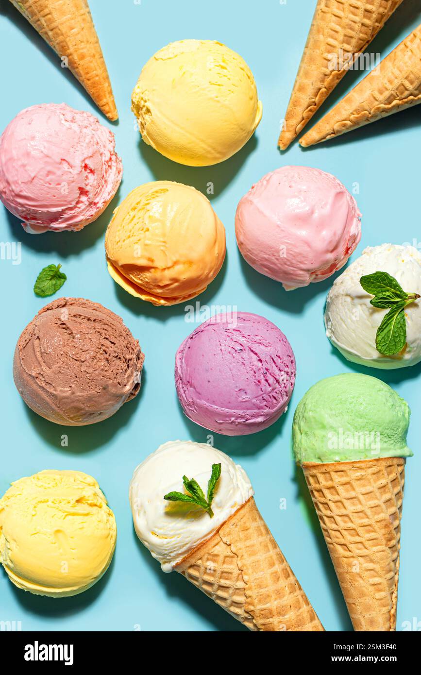 Assorted scoops of ice cream on blue background, top view. Various ice creams or gelato with ...