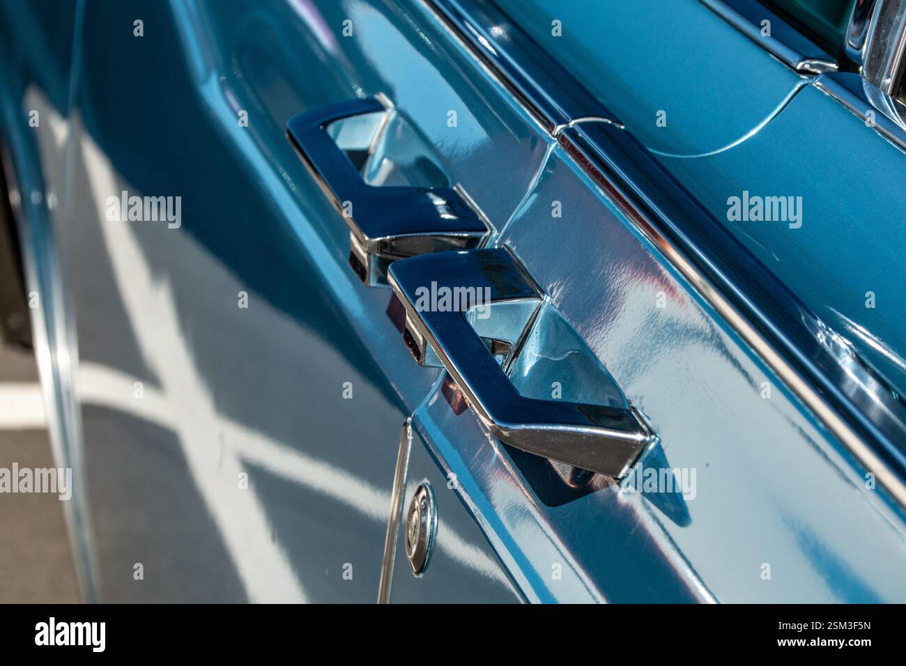 Chrome door handles on a classic blue car with suicide doors. The car ...