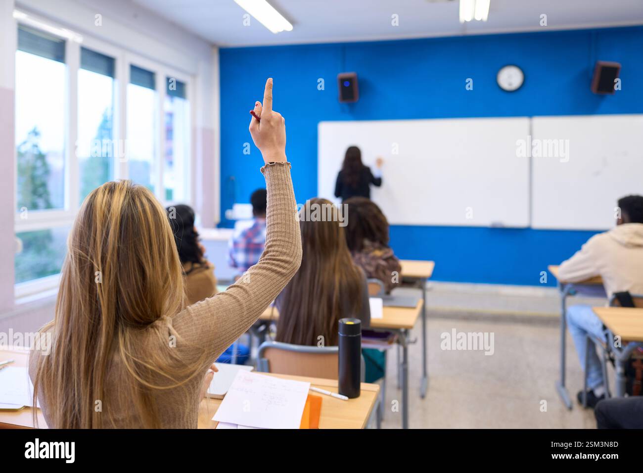High school student raising hand in classroom during lesson Stock Photo ...