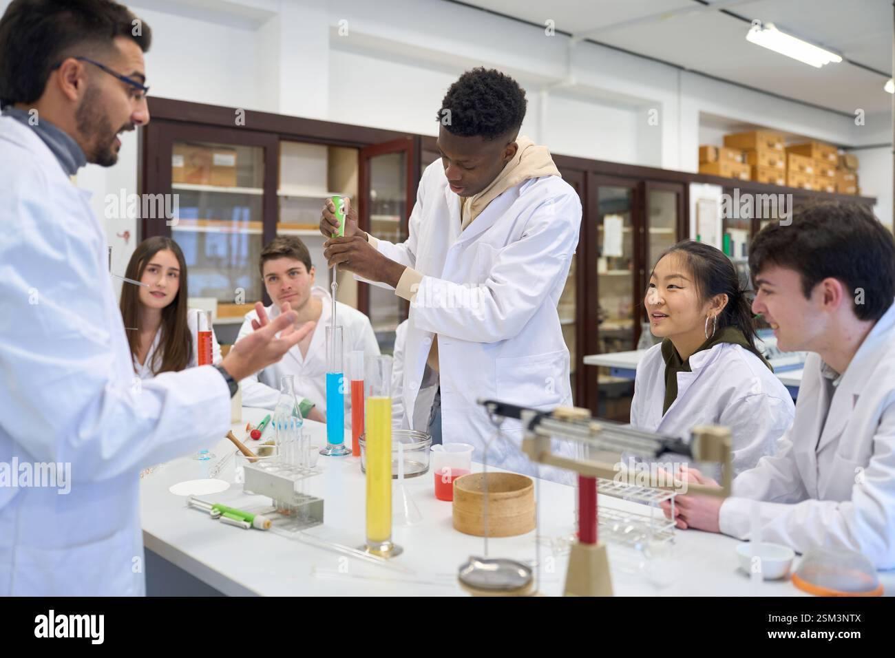 Chemistry teacher explaining experiment to students in laboratory Stock Photo - Alamy