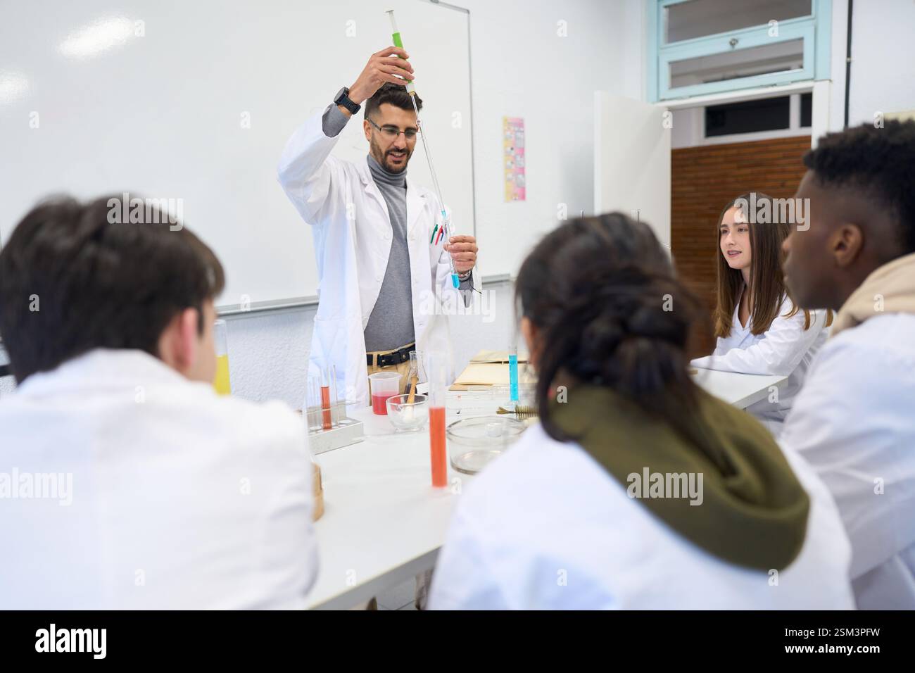 Chemistry teacher making experiment with students in laboratory ...