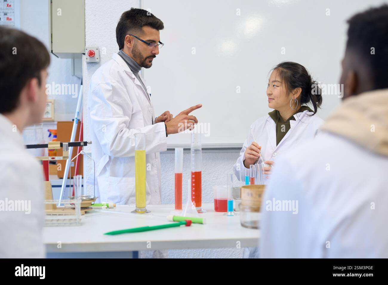 Chemistry teacher explaining experiment to students in laboratory Stock ...