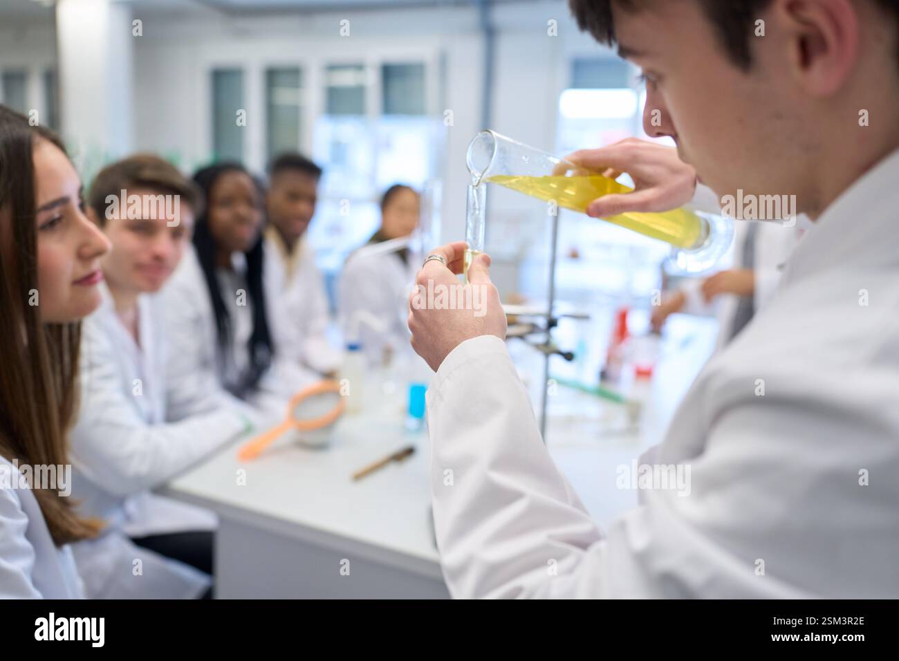 Chemistry student pouring liquid into test tube during experiment at ...