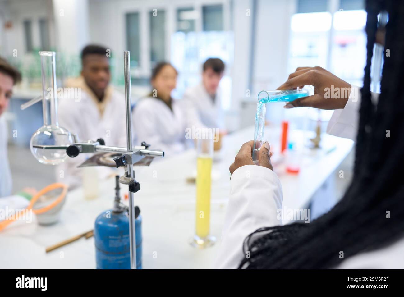 Chemistry student pouring liquid into test tube during experiment in ...