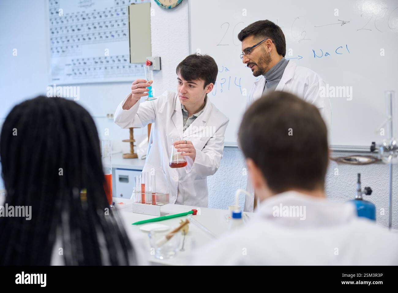 Chemistry students and teacher performing experiment in laboratory ...