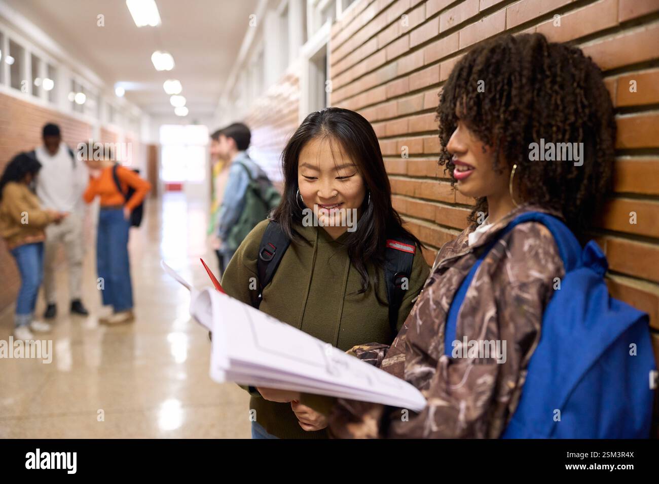 Two smiling students reviewing notes in university hallway Stock Photo ...
