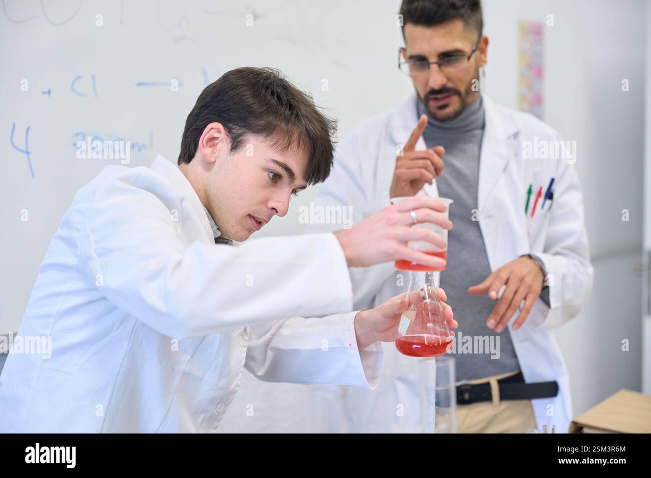 Chemistry student pouring liquid into beaker during experiment at ...