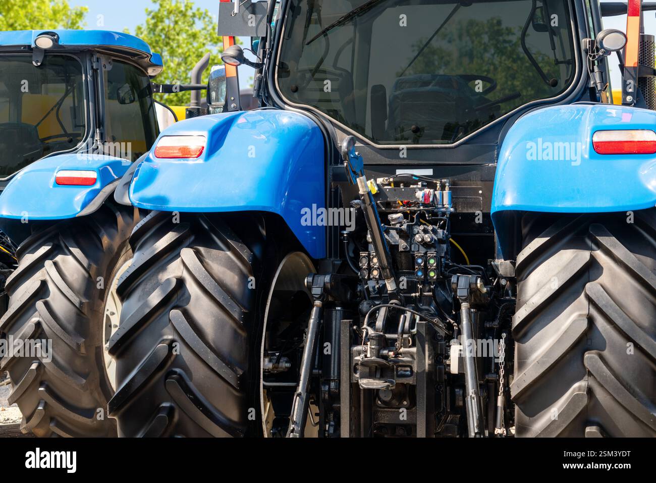 Blue tractors parked at a dealership viewed from the rear. Technical ...