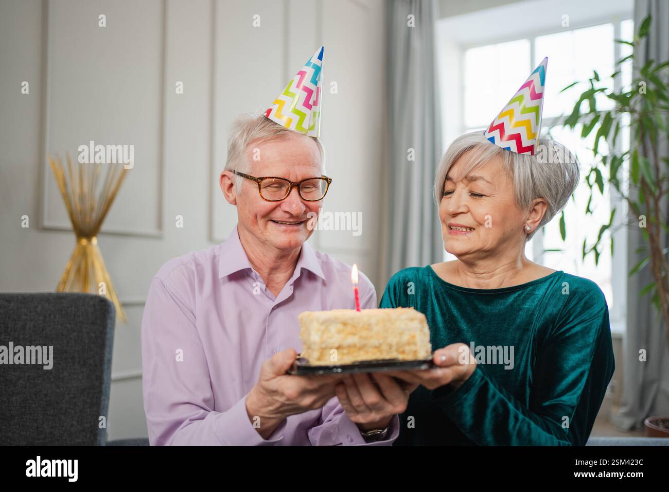 Make a wish. Family senior couple in party hat cap celebrating birthday ...