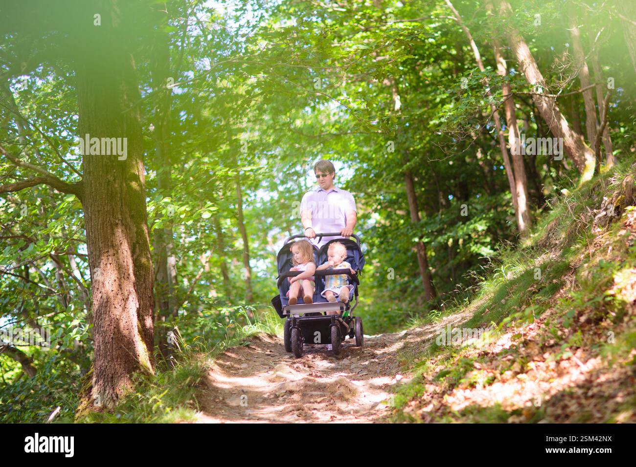 Young father walking in a park with children in stroller. Dad and kids ...