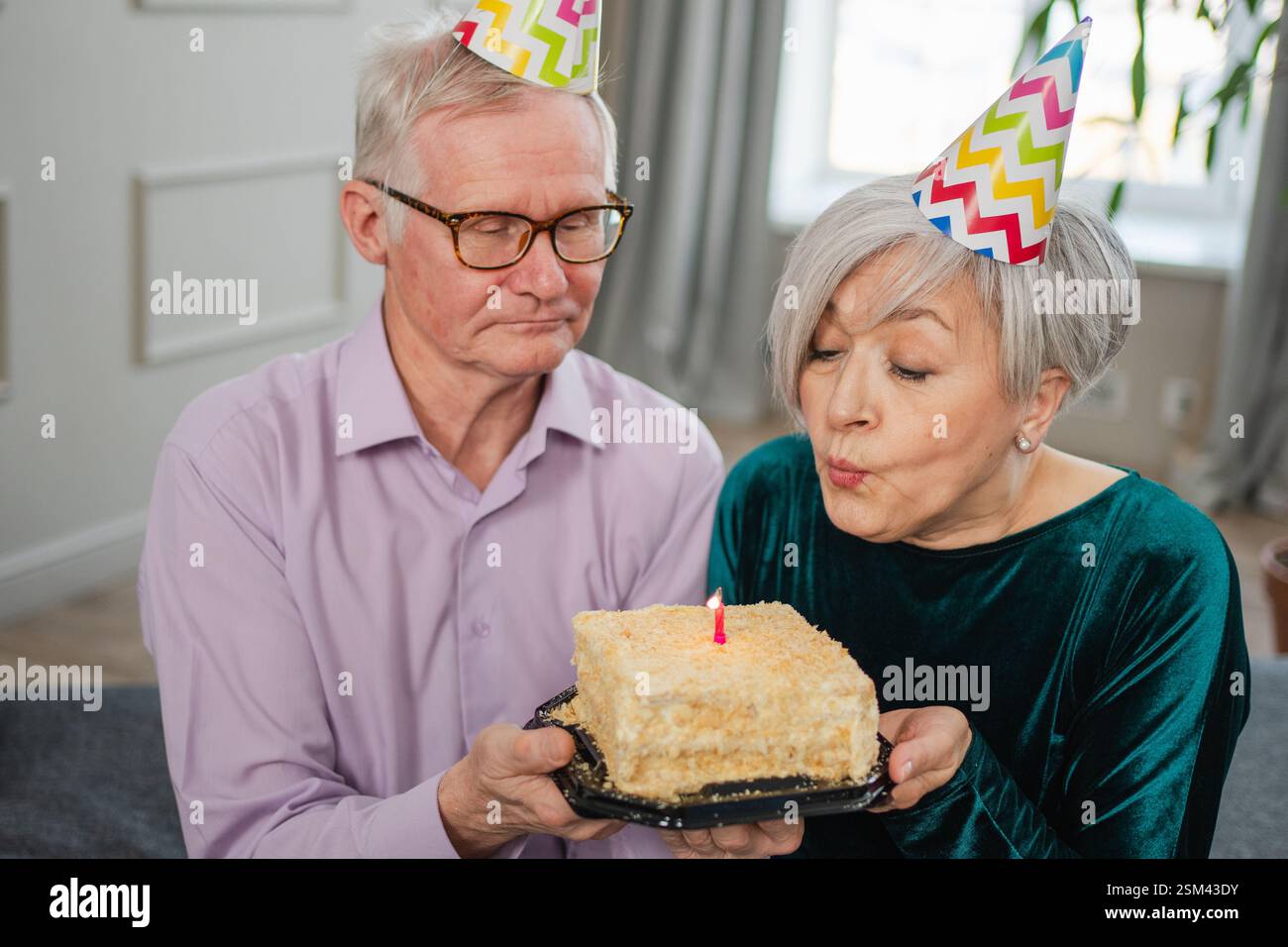 Make a wish. Family senior couple in party hat cap celebrating birthday ...