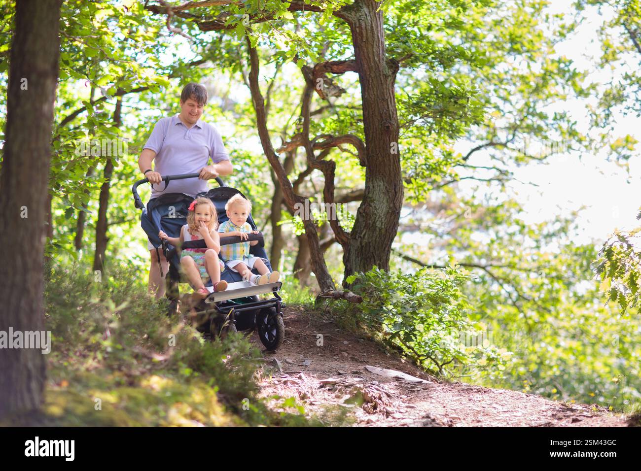 Young father walking in a park with children in stroller. Dad and kids ...