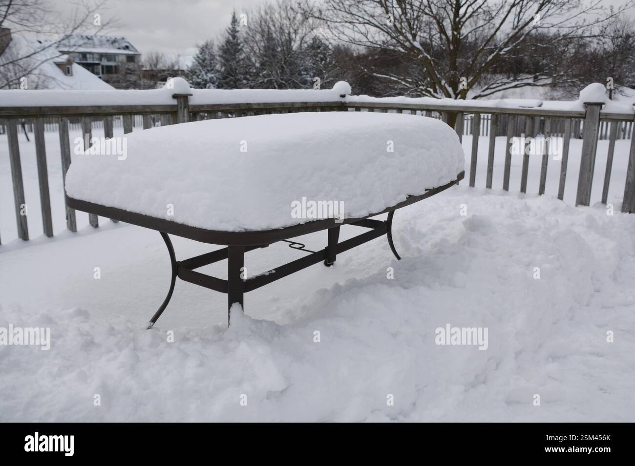 Snow accumulates on an outdoor patio table during a Canadian winter ...